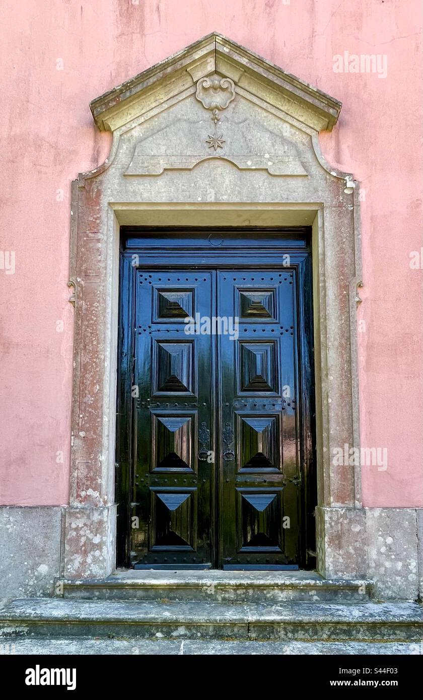 Dark wood double door entrance to a crumbling pink stone building Stock ...