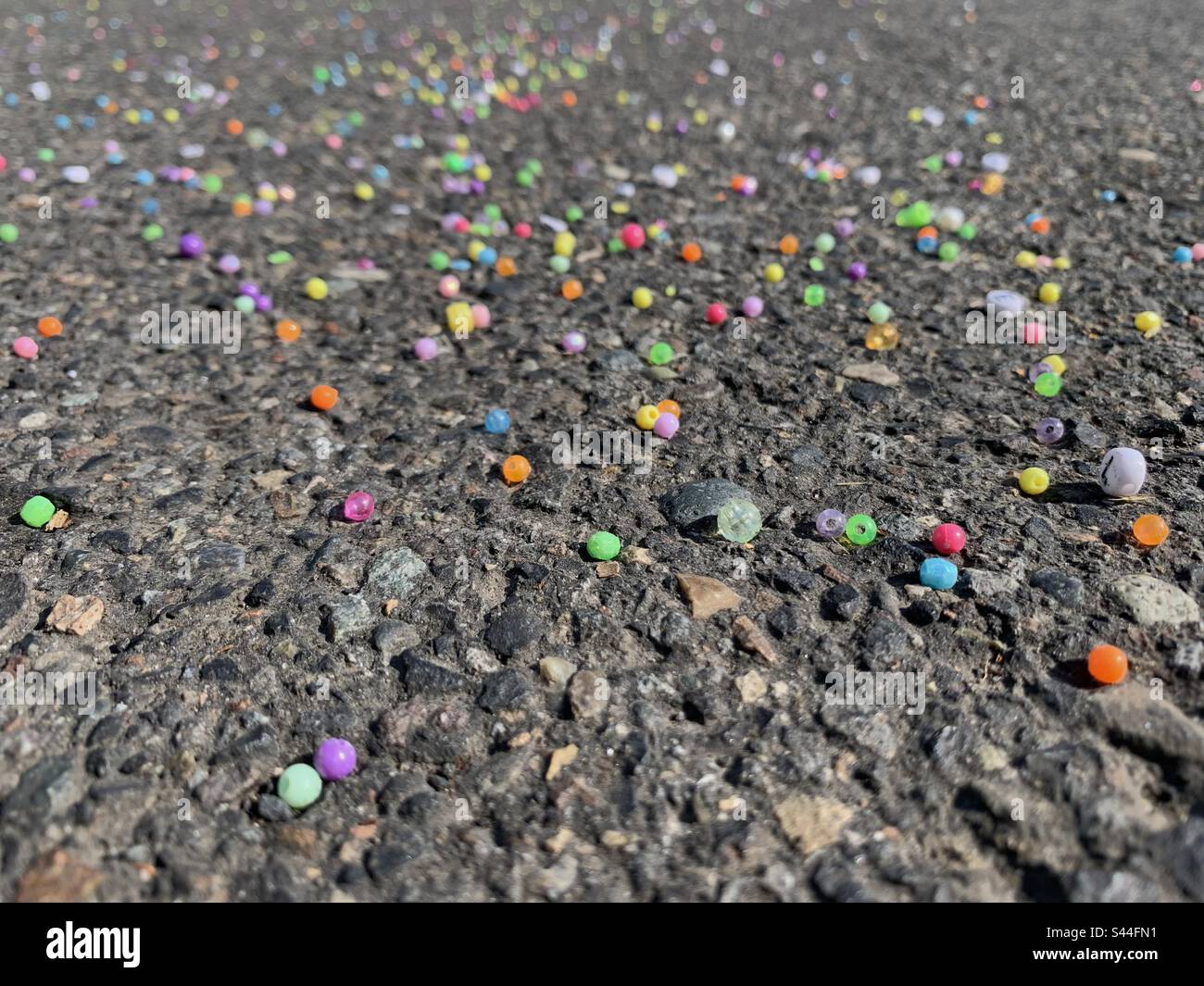 Rainbow of colorful beads scattered across street Stock Photo - Alamy