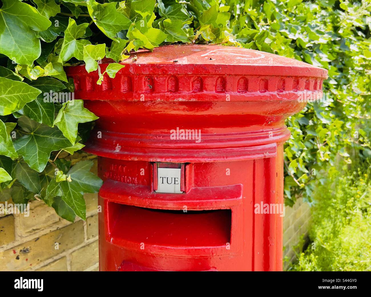 British Royal Mail postal box in red surrounded by greenery Stock Photo ...