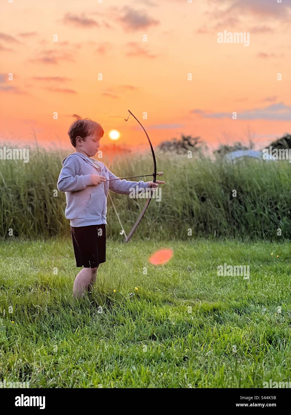 Boy try’s out a toy bow and arrow in English meadows and campsite Stock ...