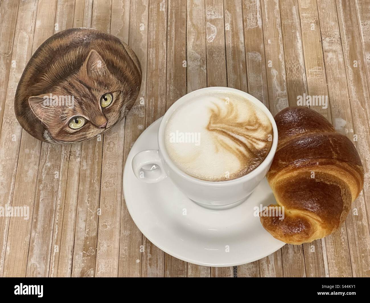 Creative and funny breakfast with cappuccino, croissant and a hand ...