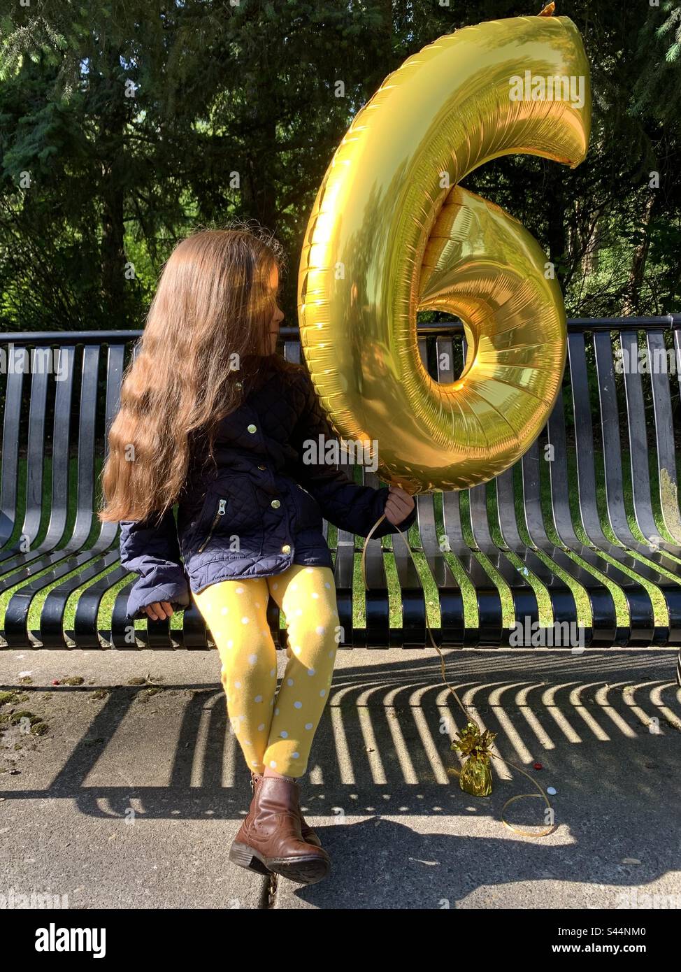 Little girl sitting on bench with 6th birthday balloon Stock Photo - Alamy