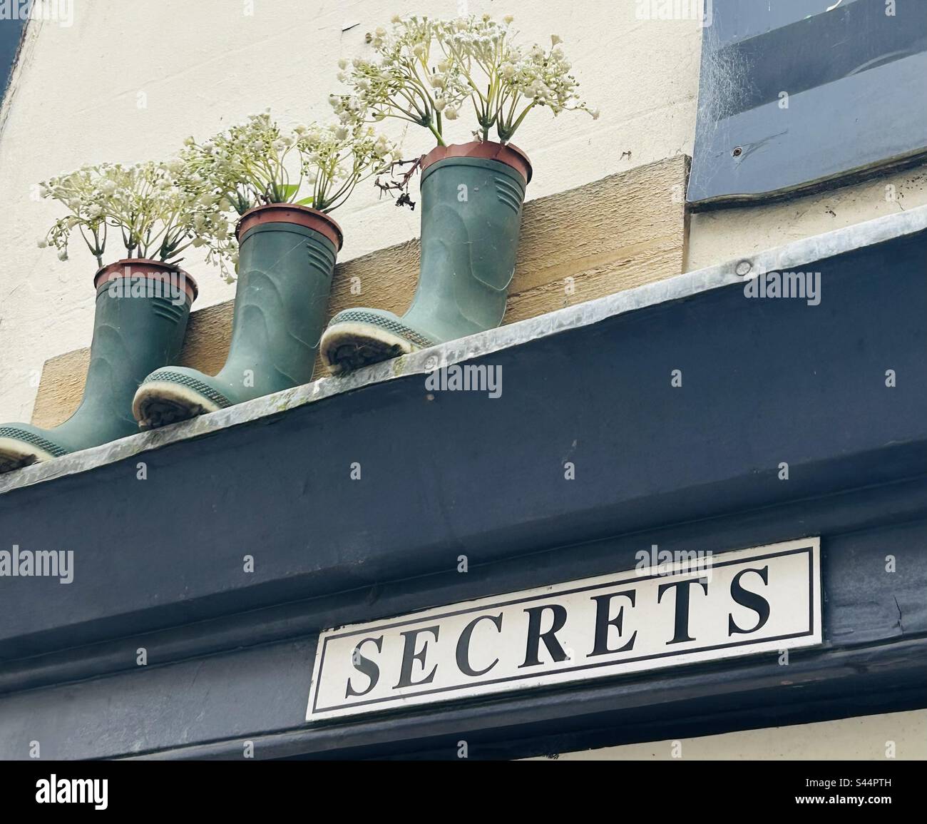 Secrets sign above a shop in Robinhoods Bay, with wellies and plants ...