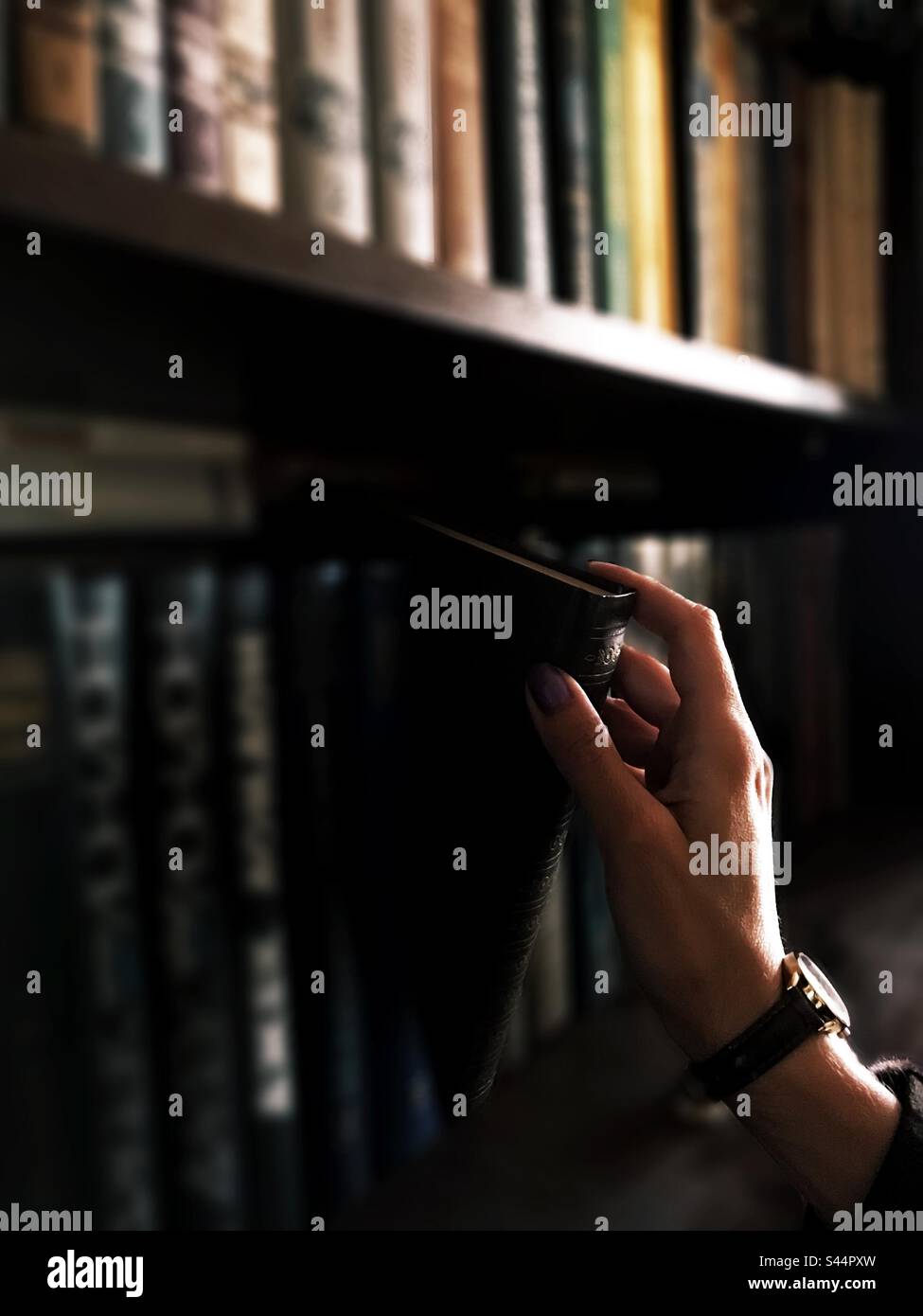 Female hand taking a book from a bookshelf Stock Photo - Alamy
