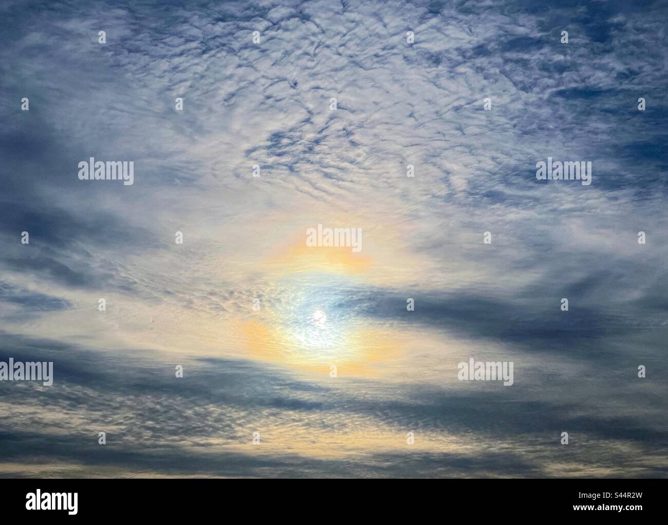 Solar halo and iridescent clouds seen in cloudy, early morning sky due ...