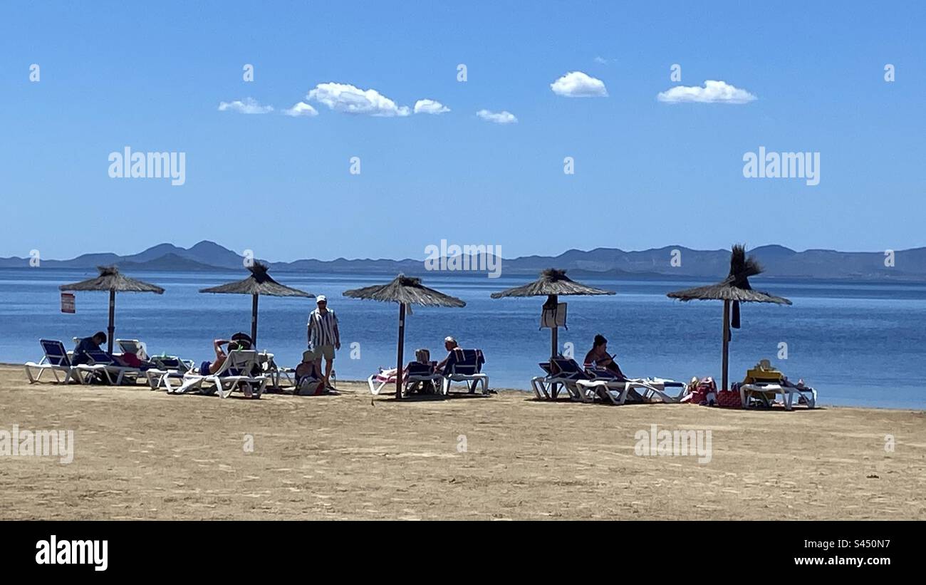 Sunbathers on the beach with a blue sky and white clouds overhead in Lo ...