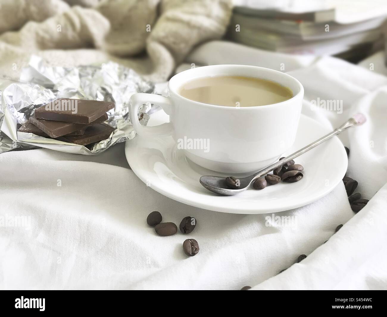 White cup of coffee with milk and coffee beans and chocolate in white ...