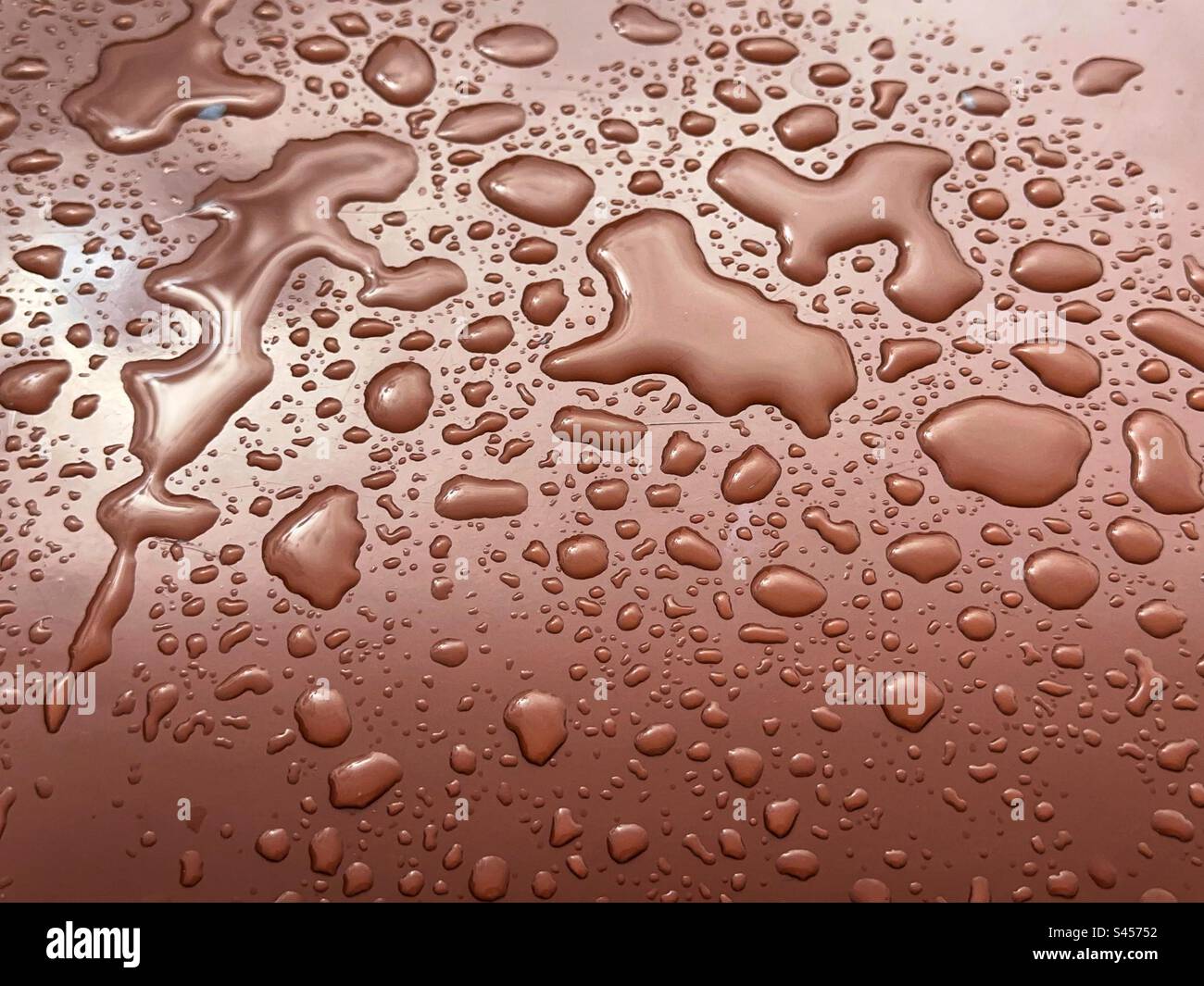 Droplets of water on a shiny brown surface after a rain shower ...