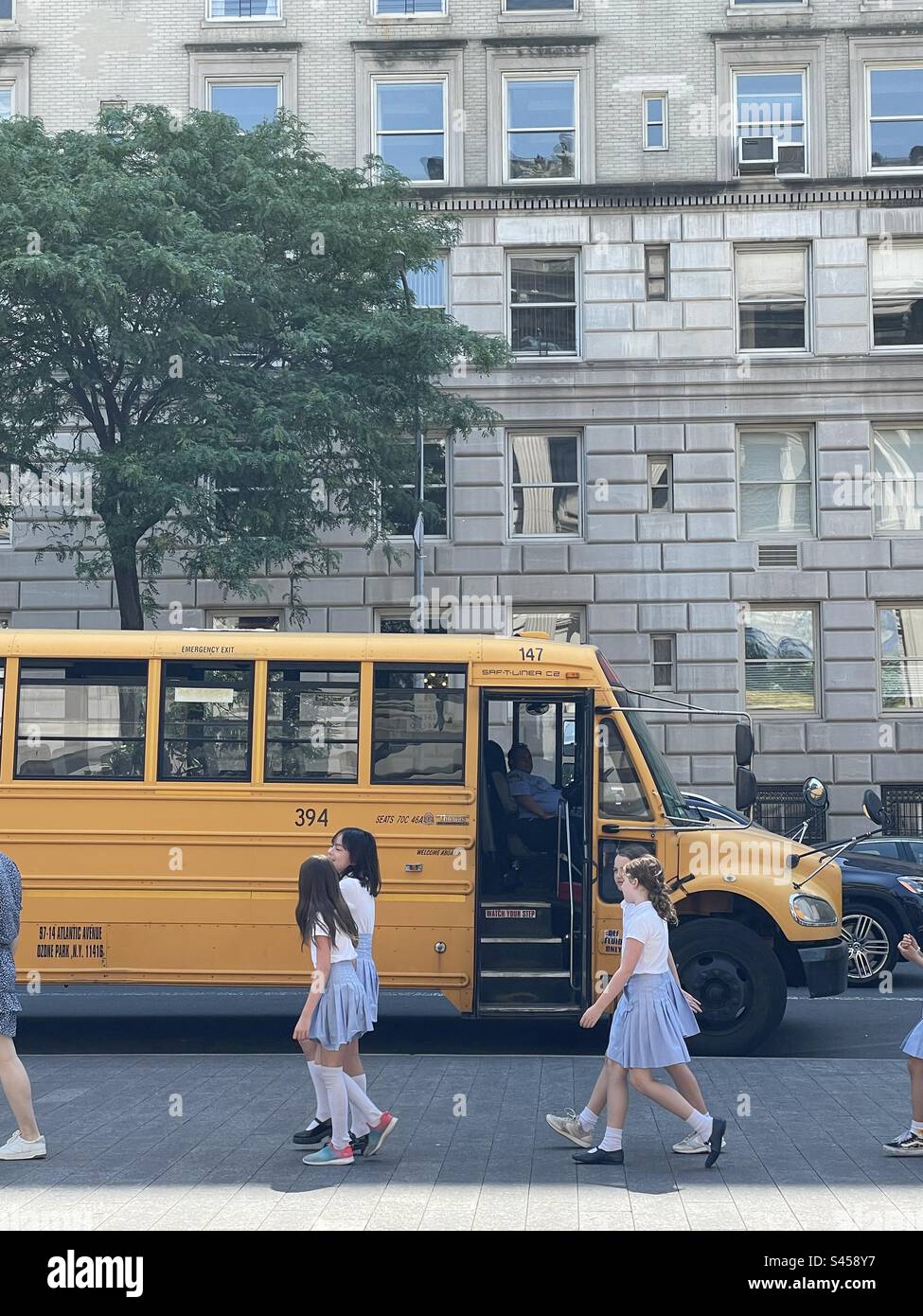 Uniformed school girls walking in front of a yellow school bus Stock ...