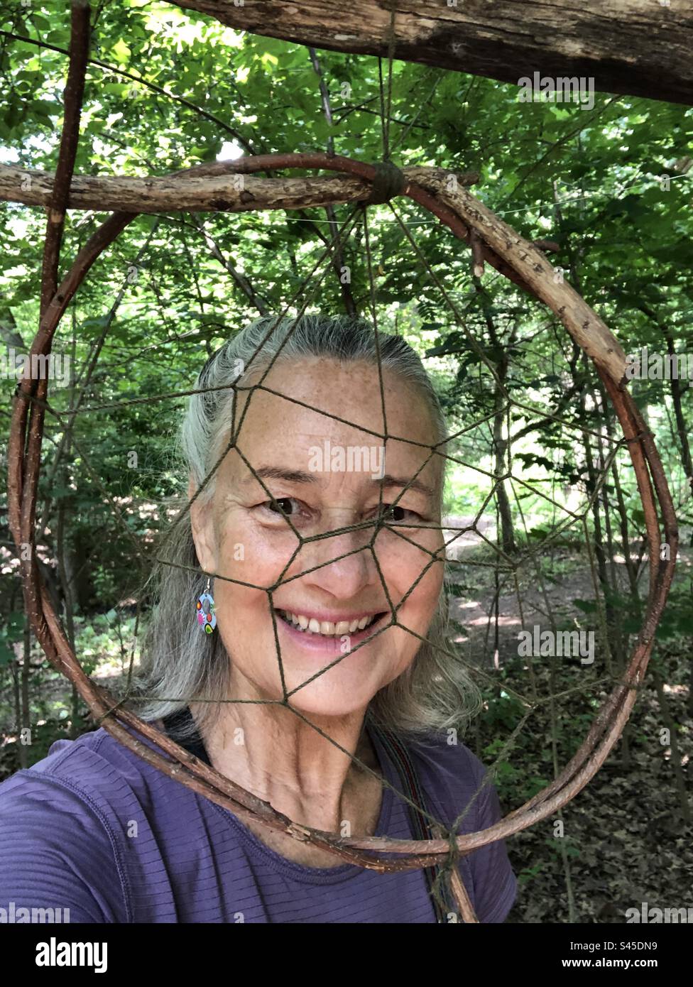 Woman looking through a dream catcher hanging in the woods Stock Photo ...
