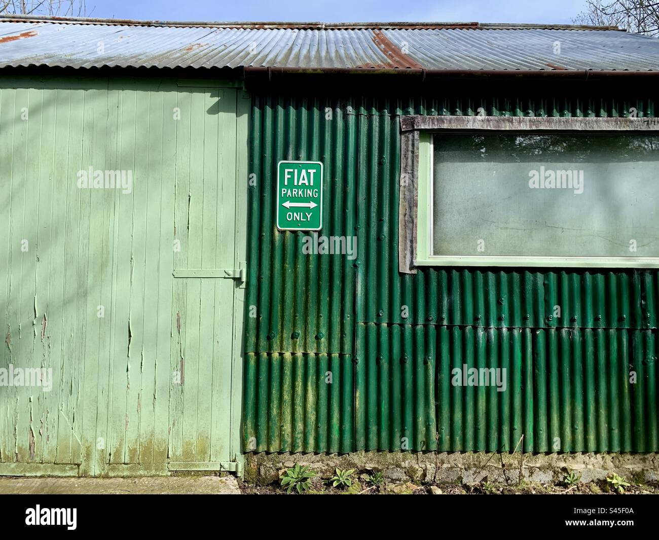 Green corrugated iron garages with Fiat parking sign Stock Photo - Alamy