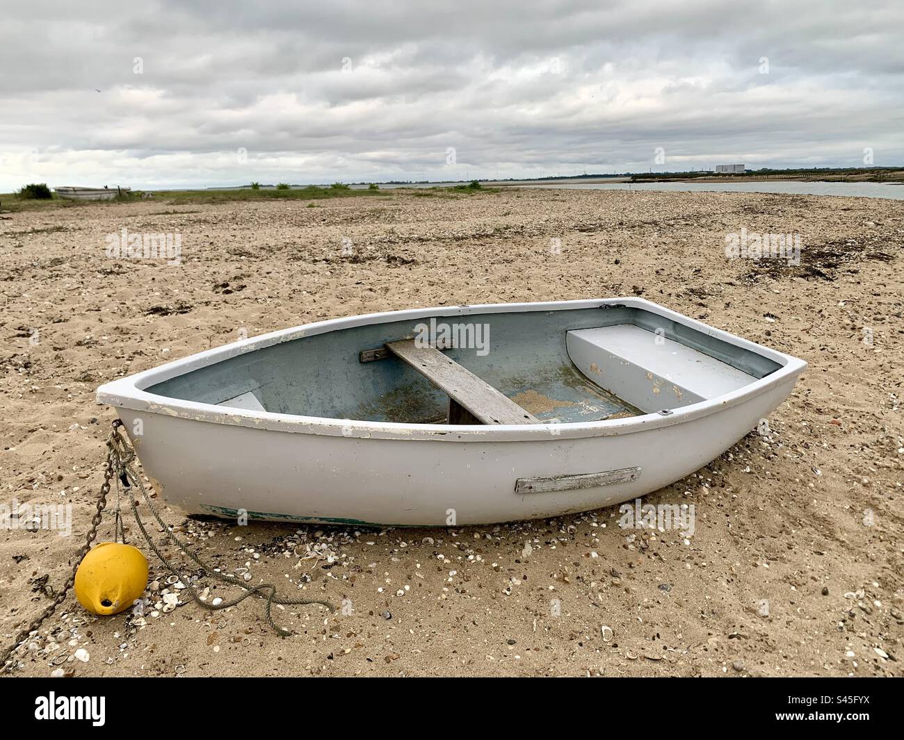 Small rowing boat moored on beach with yellow buoy, west Mersea, Essex ...