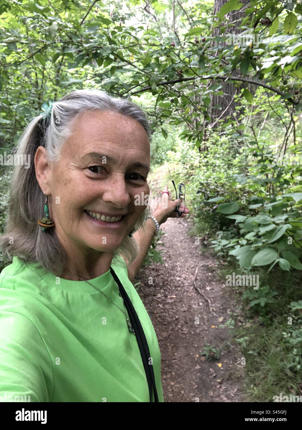 A woman blending in with nature and pointing towards a path in the ...