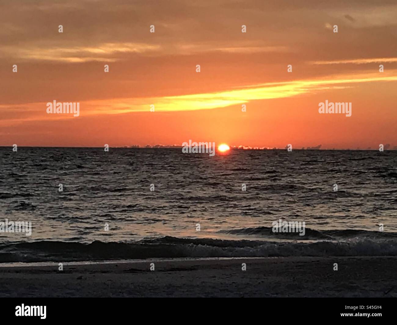 Sun disappearing along the ocean line Stock Photo - Alamy