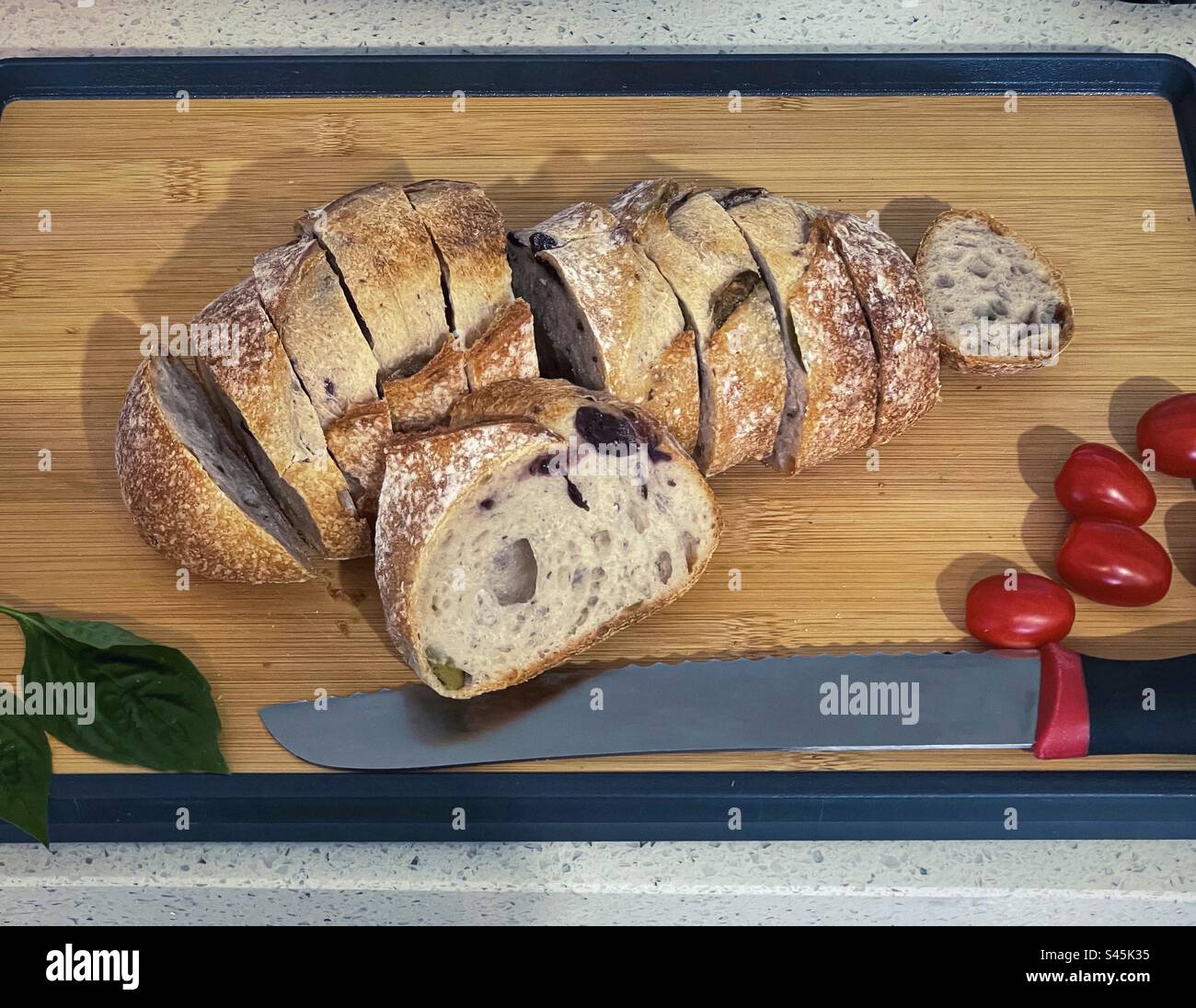 High angle view of sliced, crusty olive sourdough loaf of bread with ...