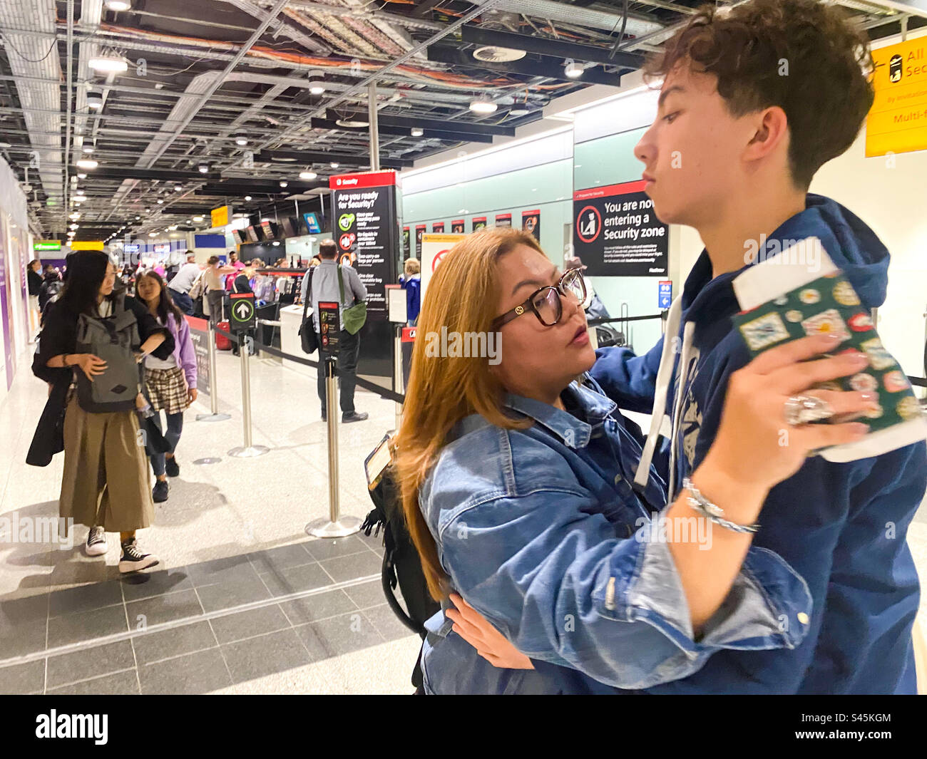 A mother and teenage son saying goodbye at Heathrow Airport Terminal 3 ...