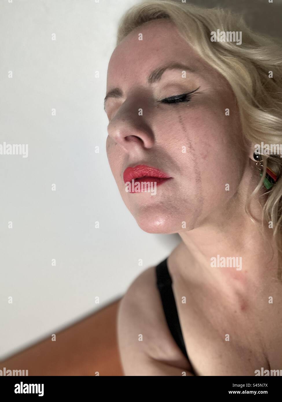 Crying blonde woman in black with red lips and streaking mascara Stock ...