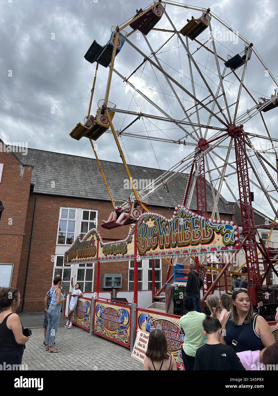 Fairground in the village square, England, July 2023. Carnival rides ...