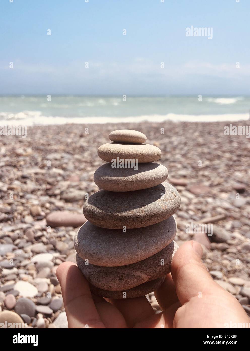 Person holding a stack of balancing pebbles. By the sea Stock Photo - Alamy