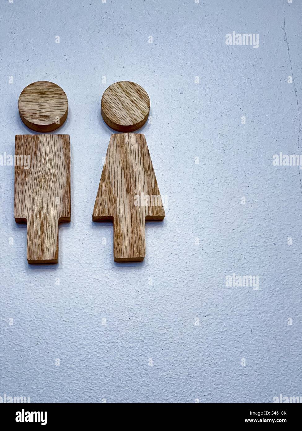 Wooden man and woman toilet signs on white wall with copy space ...