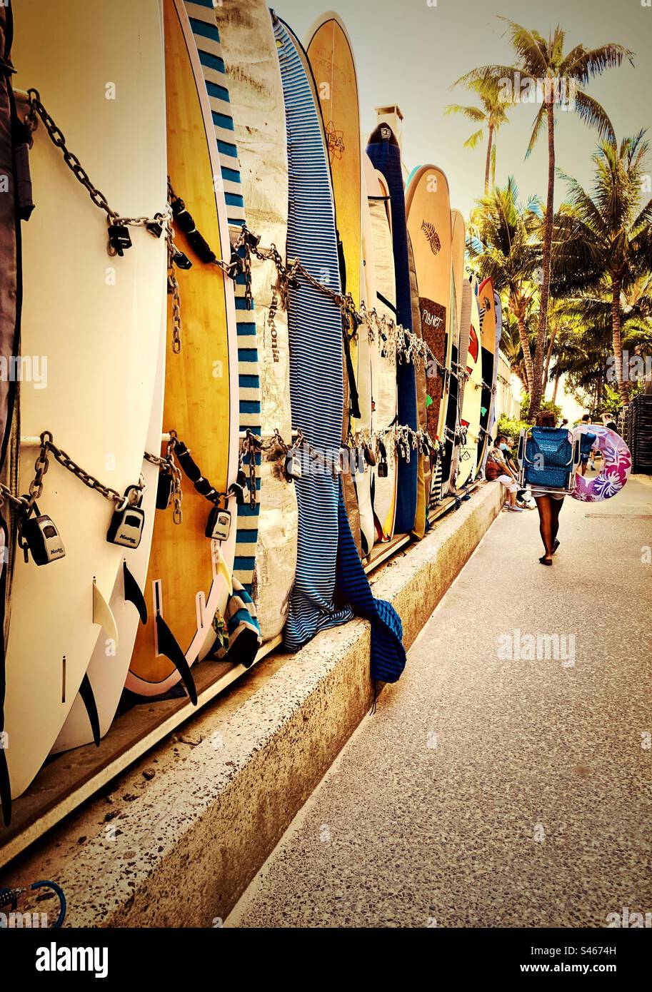 Alley way leading to Waikiki beach lined with surfboards and a woman ...