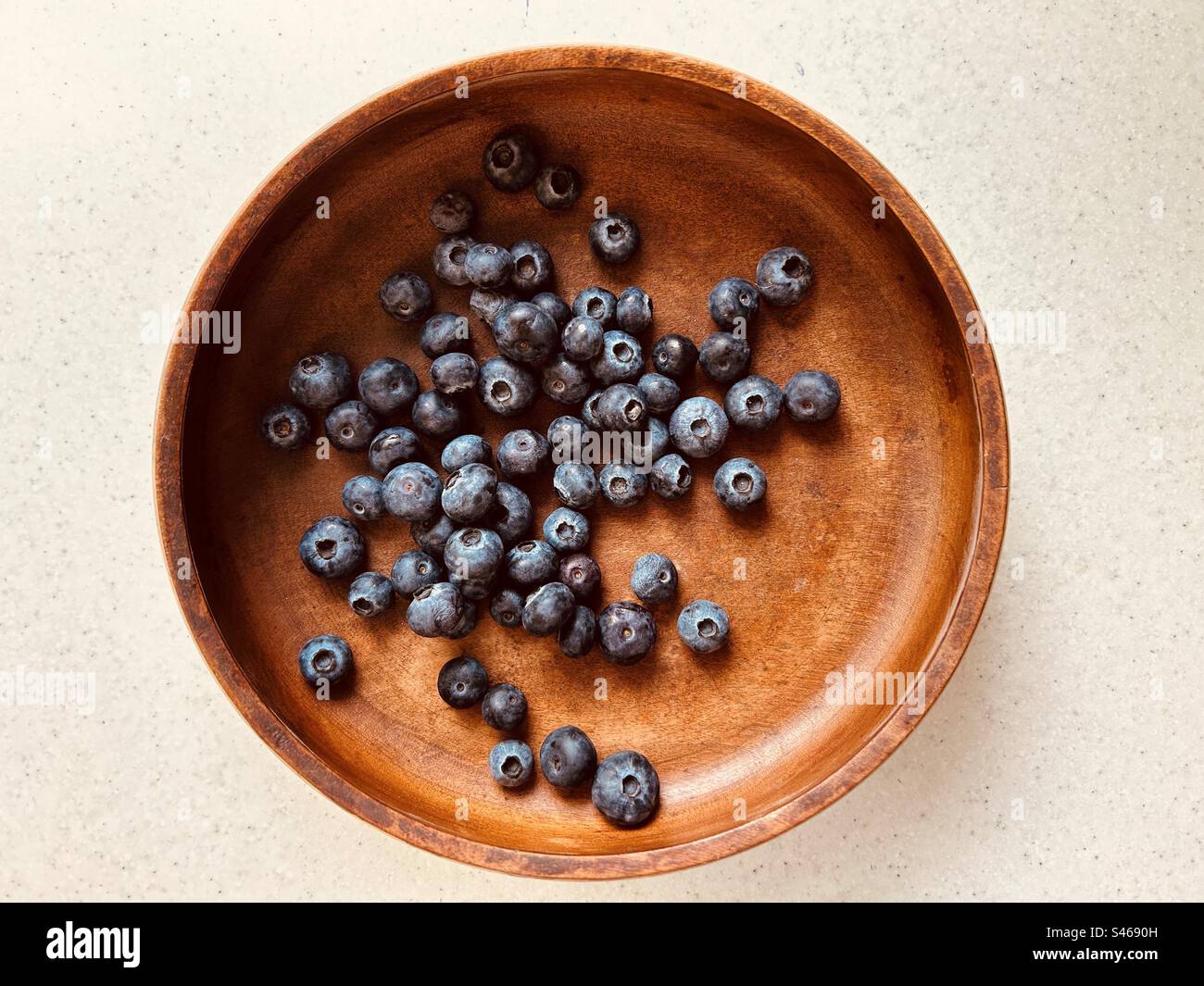 Multiple blueberries, a scatter pattern, in a circular wooden bowl ...