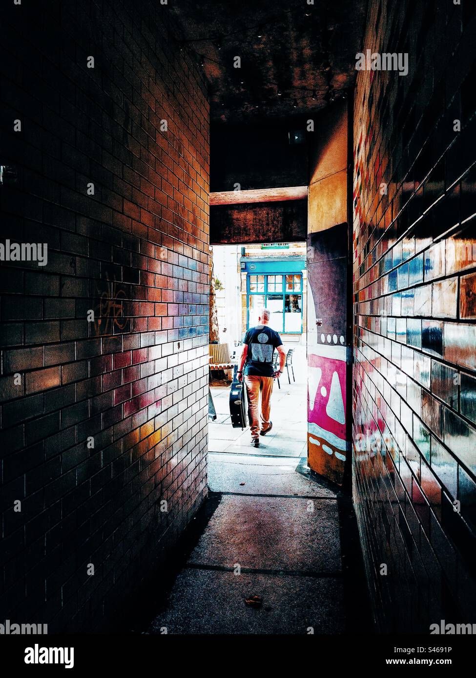 Man carrying guitar across Wind street in Swansea, UK 2023 summer. View ...