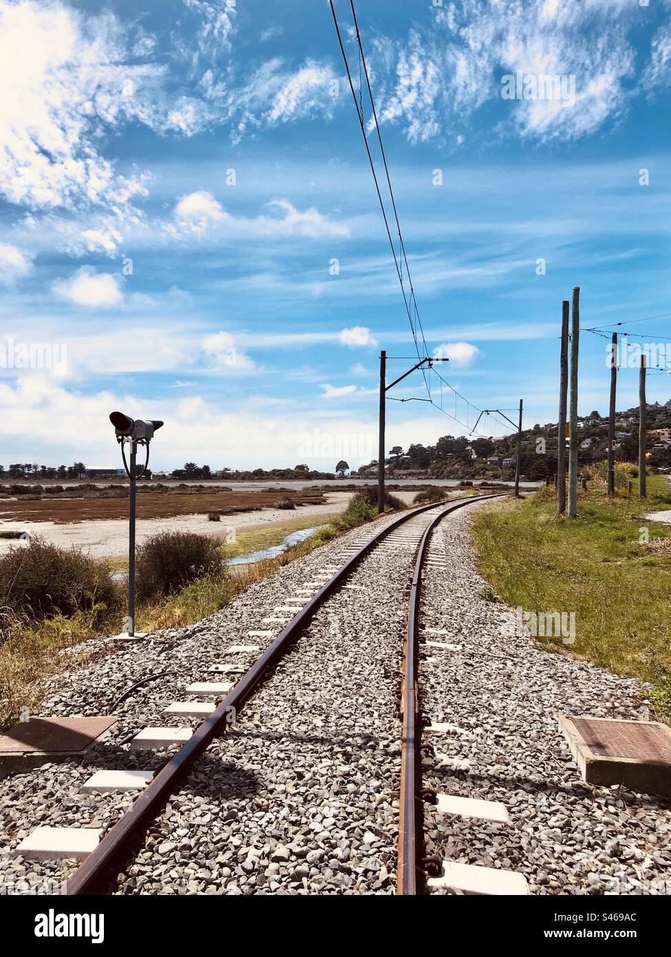 Single tram track leading off towards the horizon, an estuary to the ...