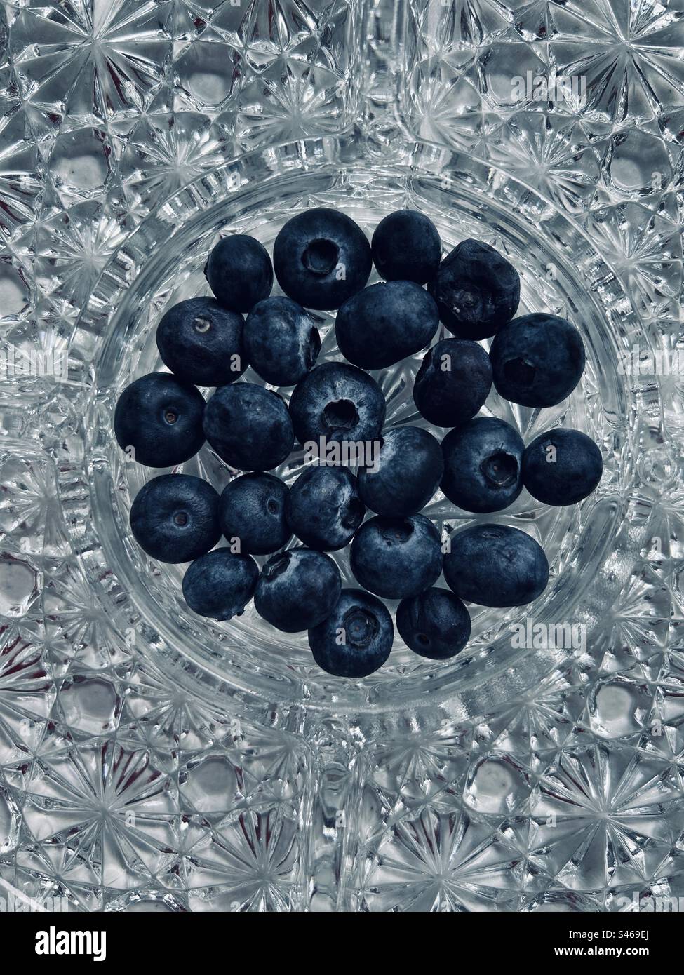 Abstract blue-tinged overhead shot of blueberries at the centre of an ...