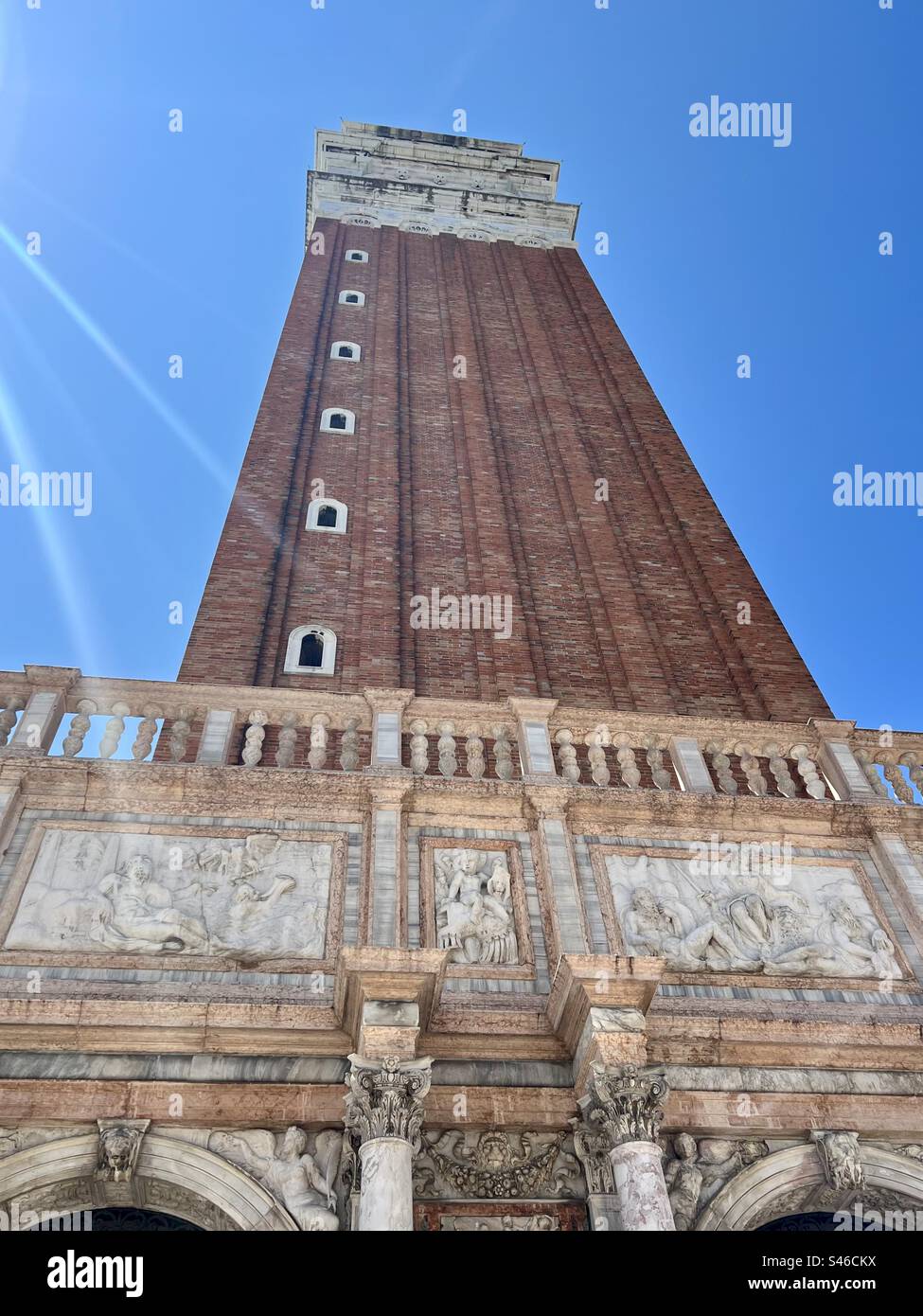 St. Mark’s Bell Tower, the Campanile, under a clear blue sky with rays ...