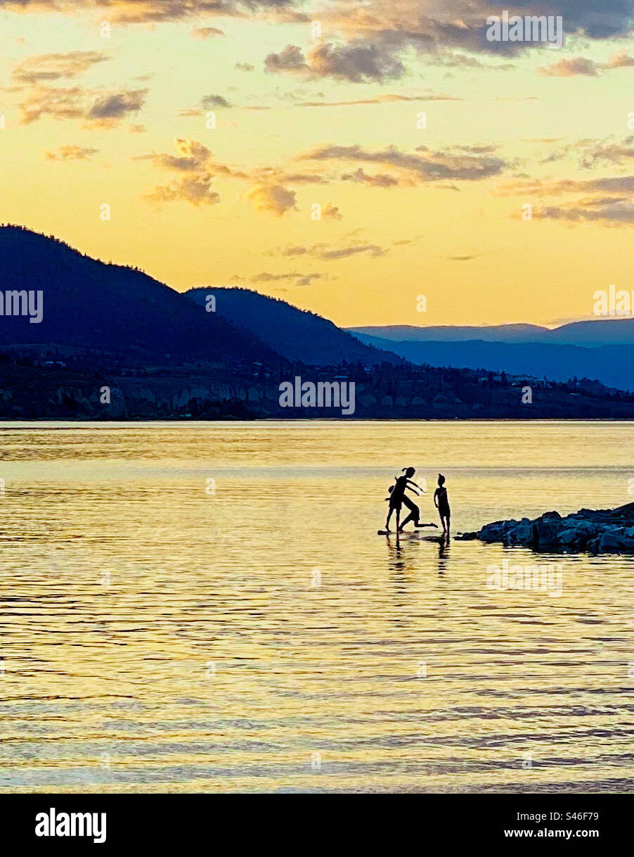 Sunset over Lake Okanagan with metal sculptures of children playing ...
