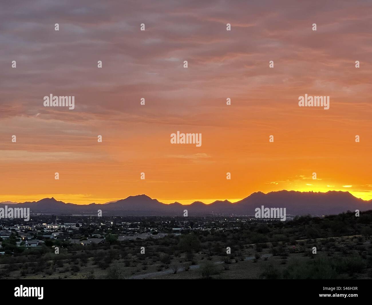 A rising sun halo over the McDowell Mountains, orange, violet, banks of ...