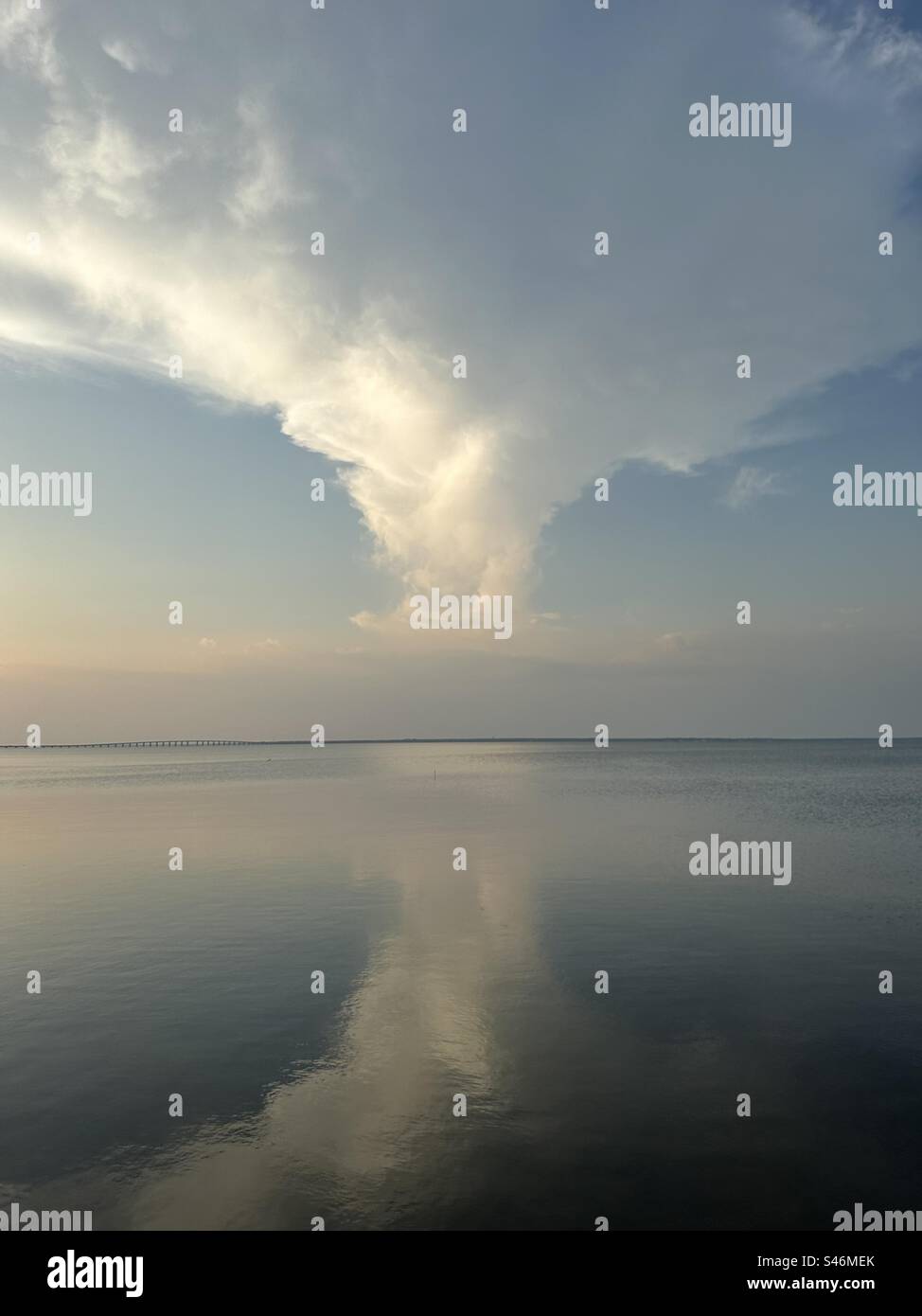 Large white cloud reflecting onto calm bay water Stock Photo - Alamy