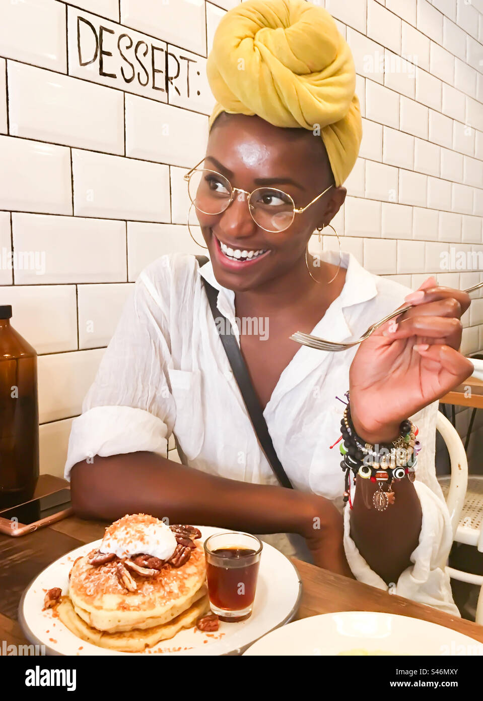 African-American woman in her 30s ready to eat a stack of pancakes in a ...