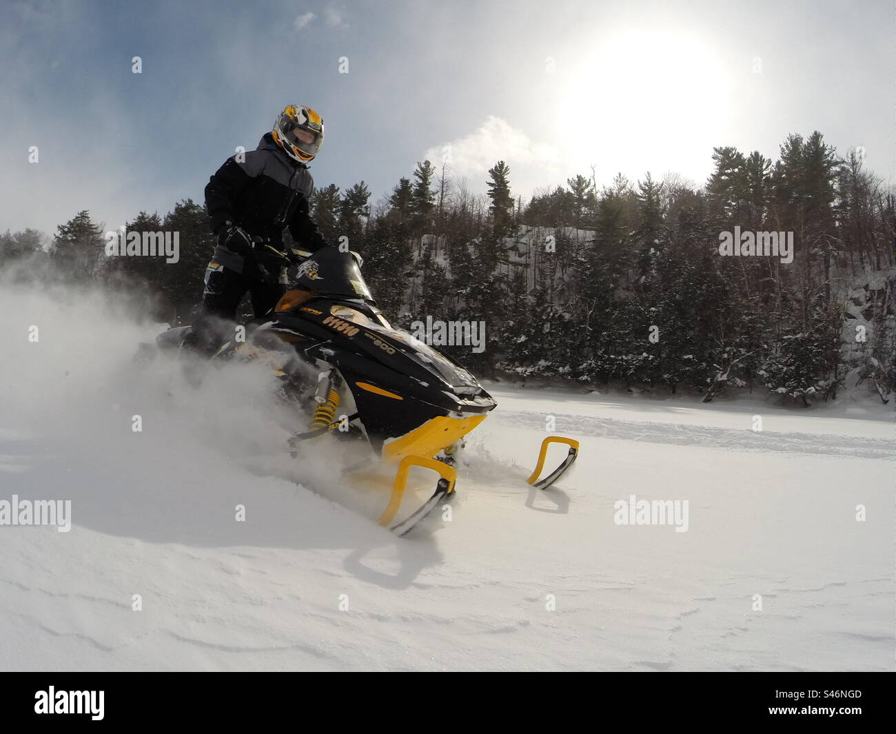 Snowmobiling across a snow covered lake, snow flying Stock Photo - Alamy