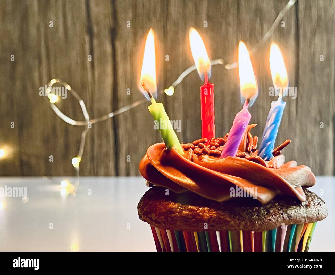 Chocolate cupcake with four birthday candles Stock Photo - Alamy