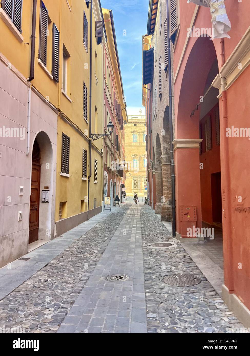 Pink, golden yellow, and red buildings on a street in Modena, Italy ...