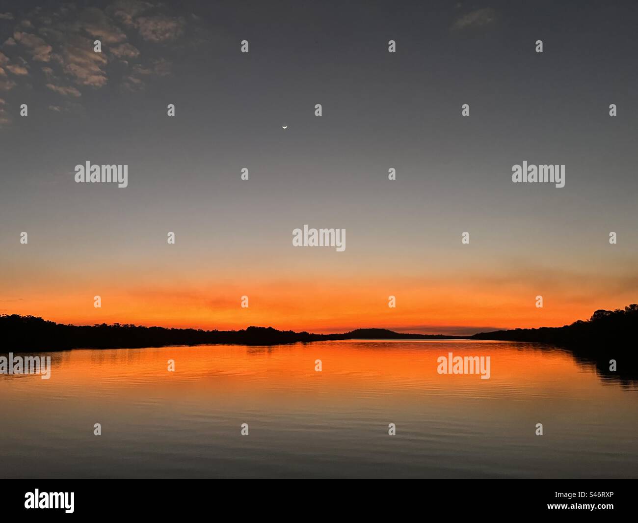 Sunset with raising moon over the water of Darwin Harbour in Australia ...