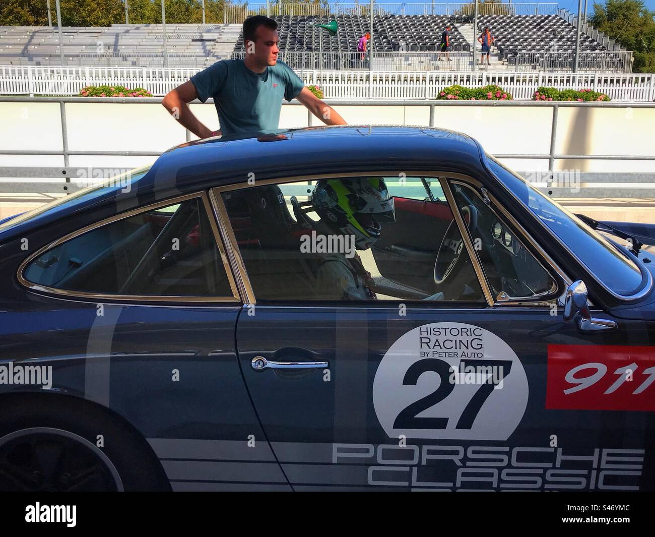 Racing driver sitting in a grey 1960s Porsche 911 in the pit lane at ...