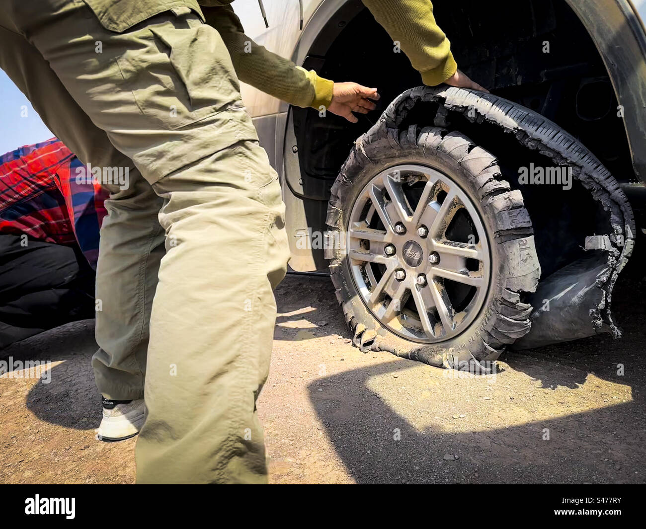 A man tries to change a tyre destroyed on the dirt roads of Namibia ...