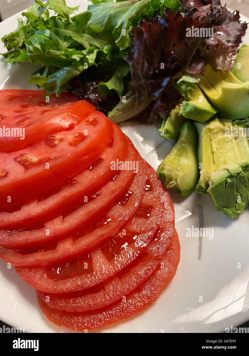 Close-up of a plate of lettuce, sliced tomato, and sliced avocado Stock ...