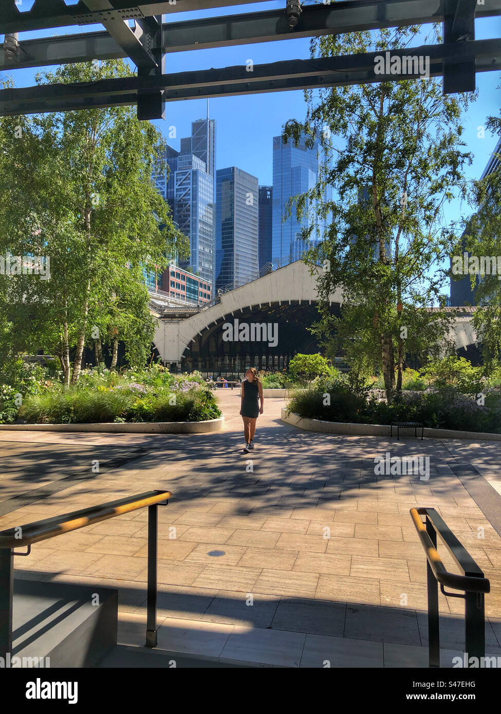 A young girl in a black dress walking at Exchange Square, Broadgate on ...