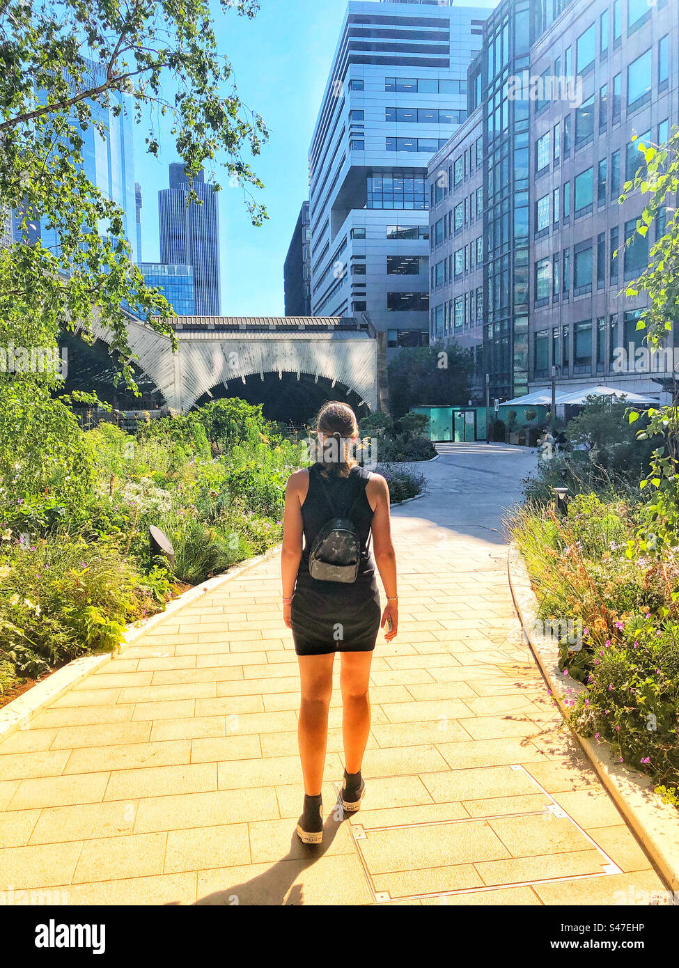 A young tourist in a black dress walking at Exchange Square, Broadgate ...