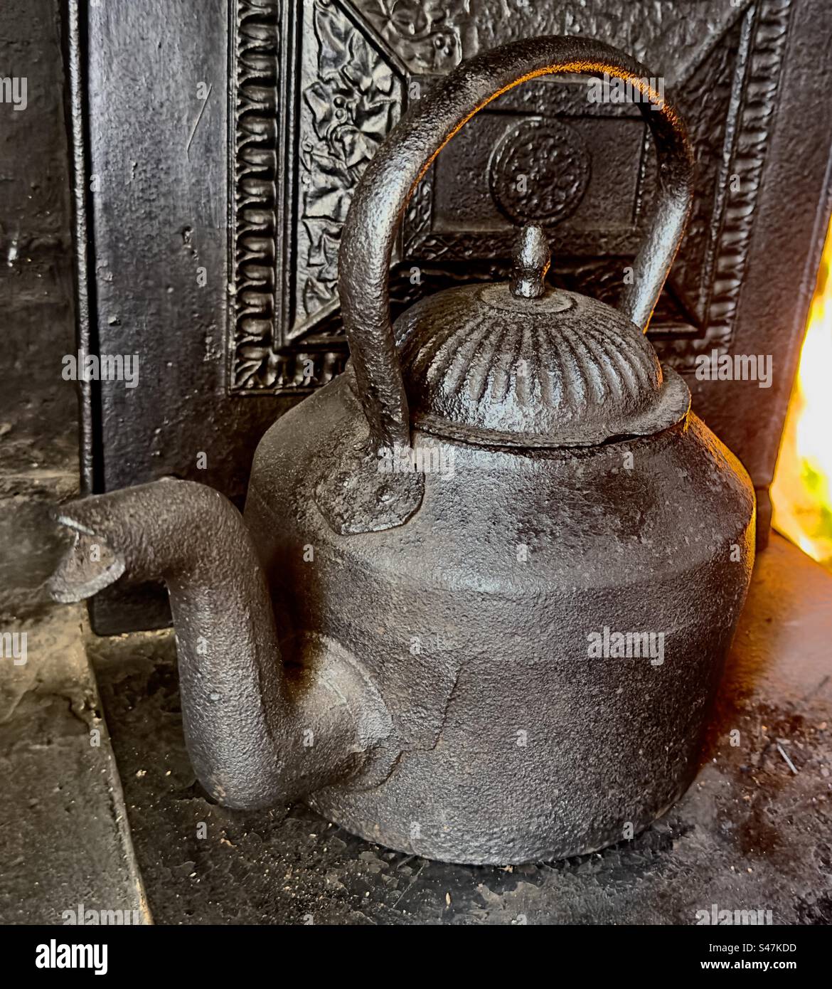 A Victorian cast iron kettle sitting on the hob is an old kitchen range ...
