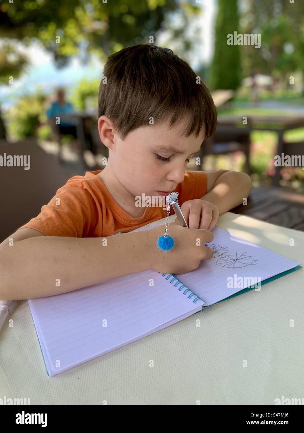 Child concentrating drawing at outdoor restaurant Stock Photo - Alamy