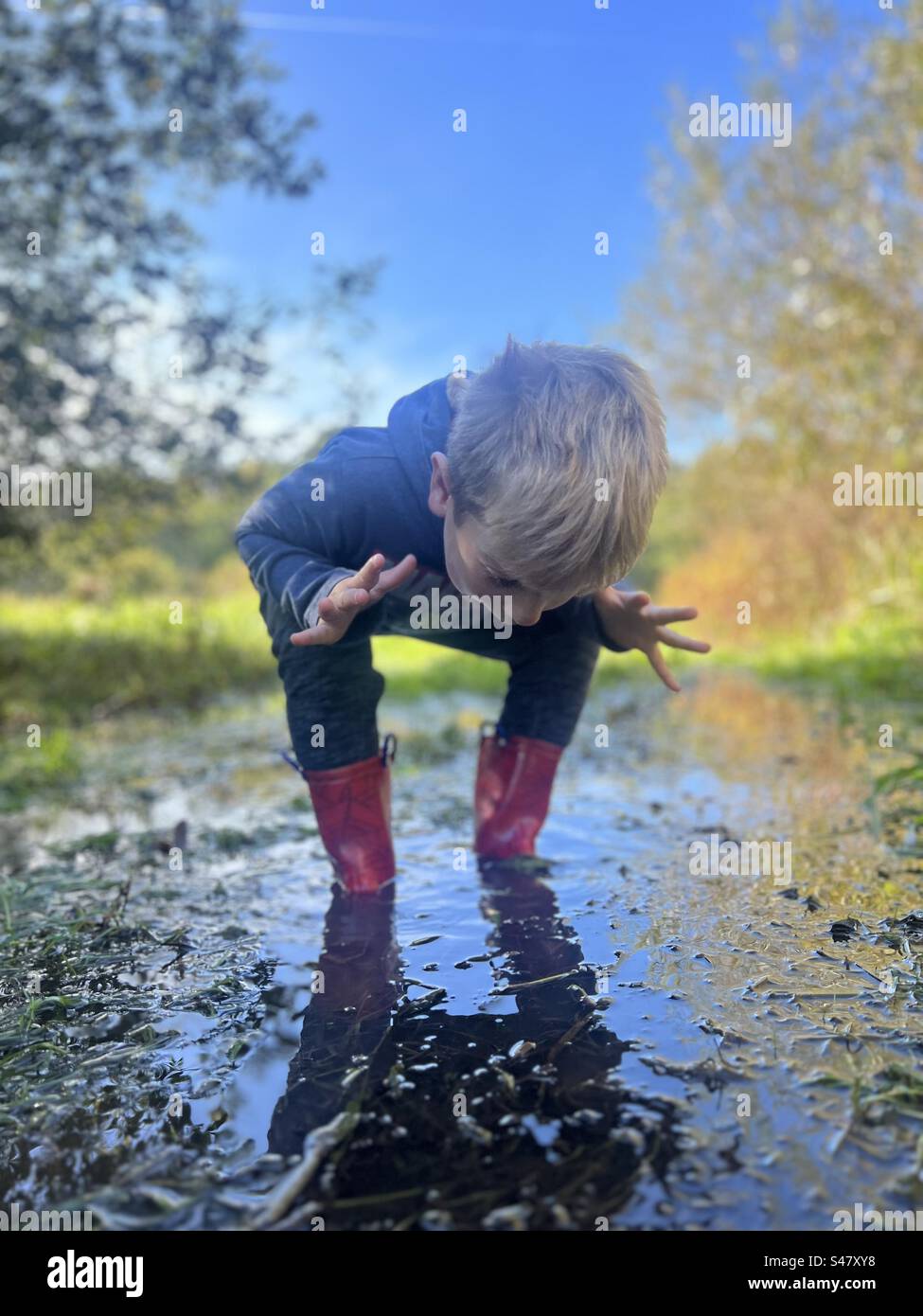 Child looks at his reflection in a muddy puddle Stock Photo - Alamy