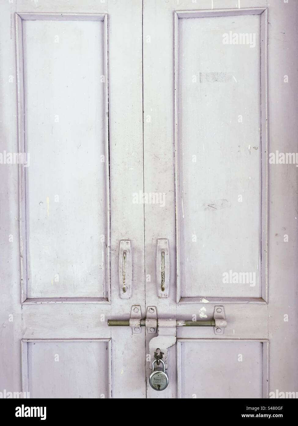 A white wooden door with an iron latch and metallic silver lock on it ...