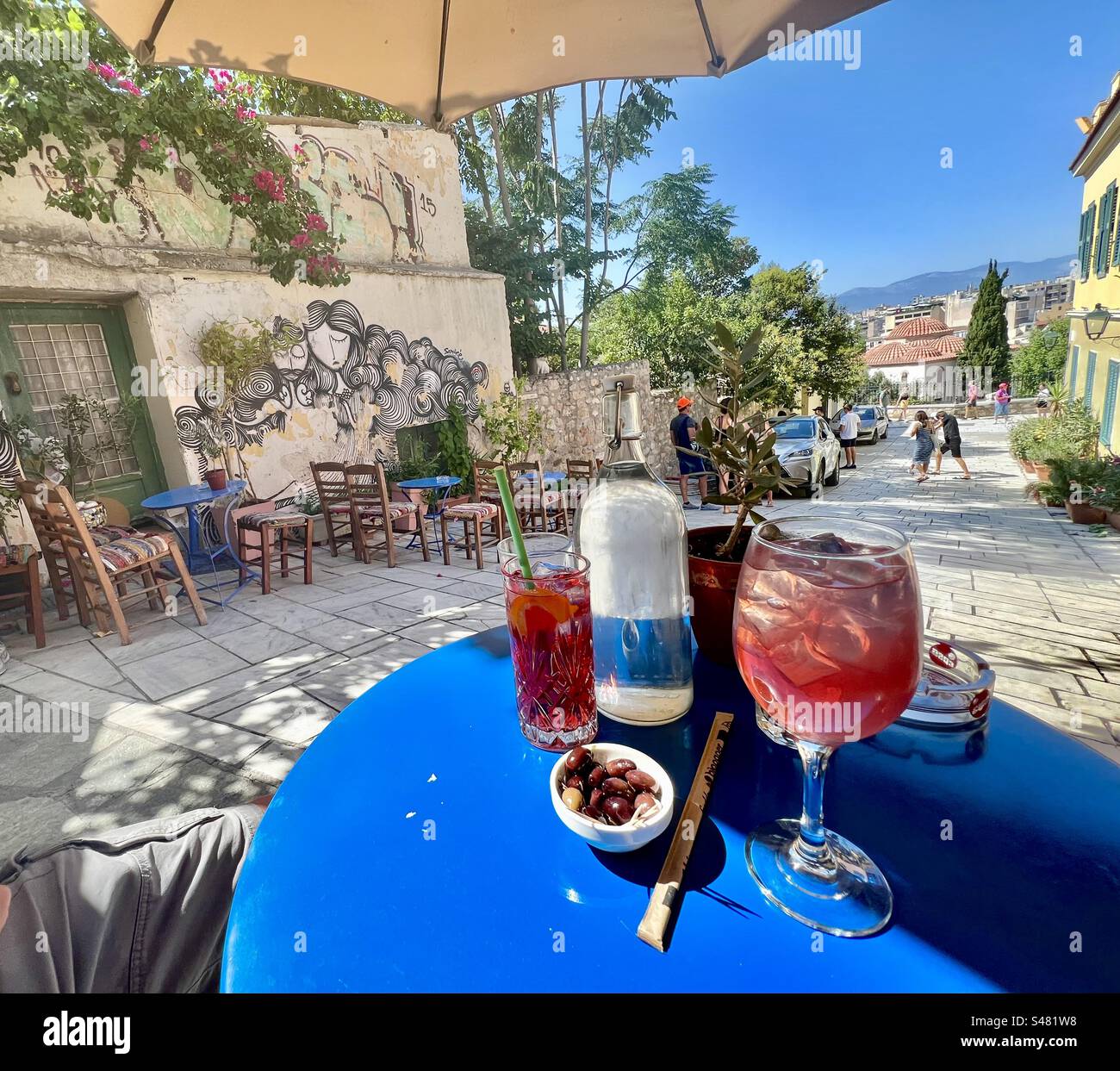 Beverages and a snack on a small blue table at a cafe on an inclined ...