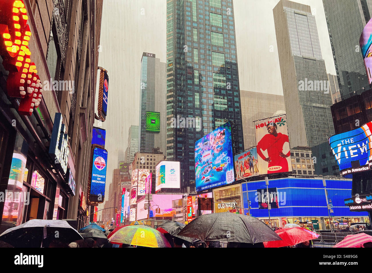 Times Square, New York in the rain with umbrellas and advertising video ...