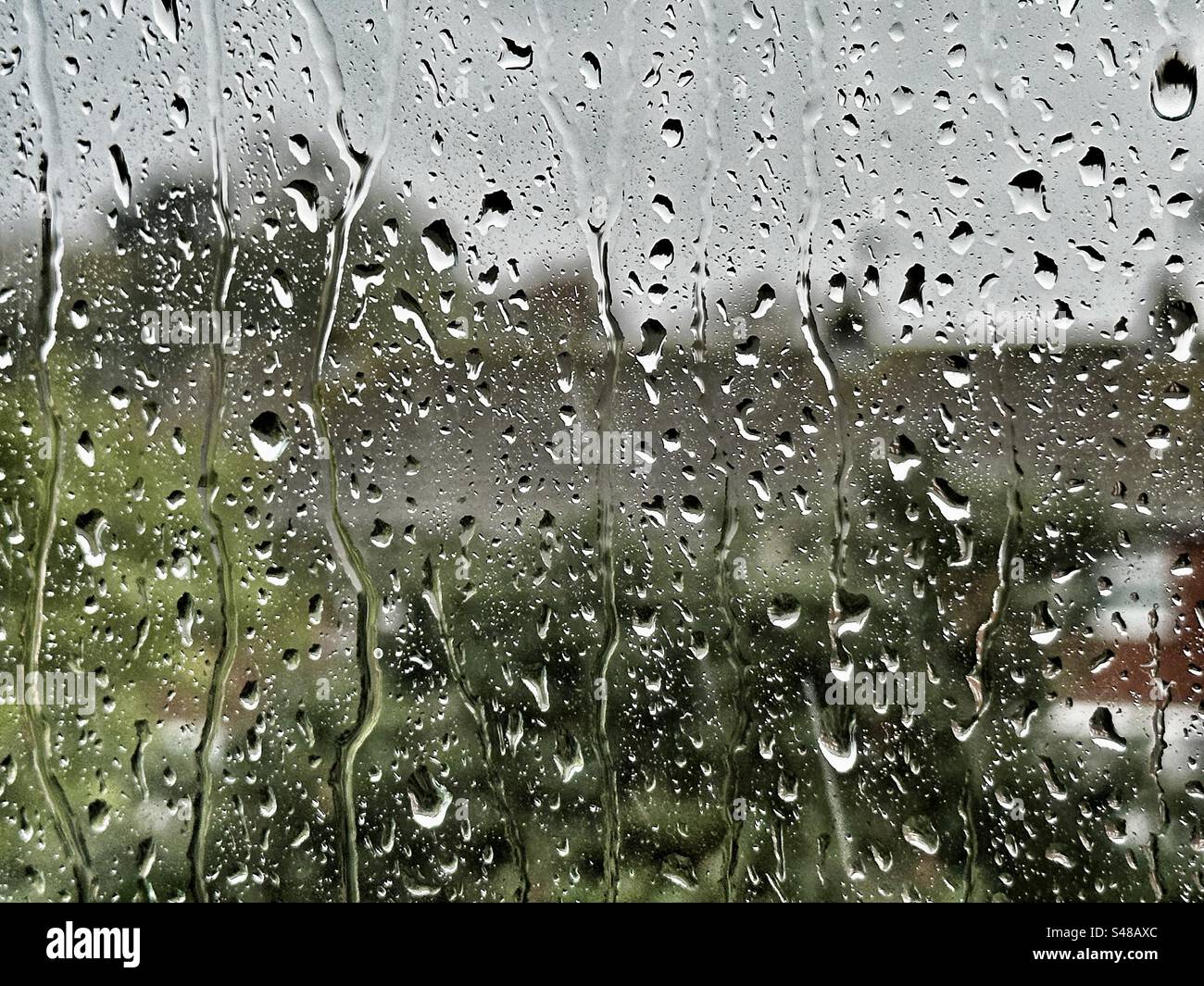 Rain on window with trees and houses in the background Stock Photo - Alamy